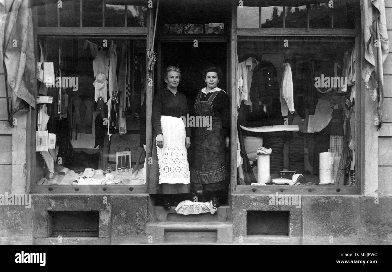 Two saleswomen are standing in the door of their fashion shop,1930s ...