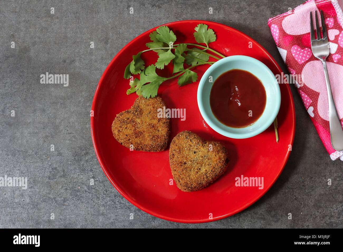Heart shaped Cutlets in red plate with sauce and cilantro / Valentines ...