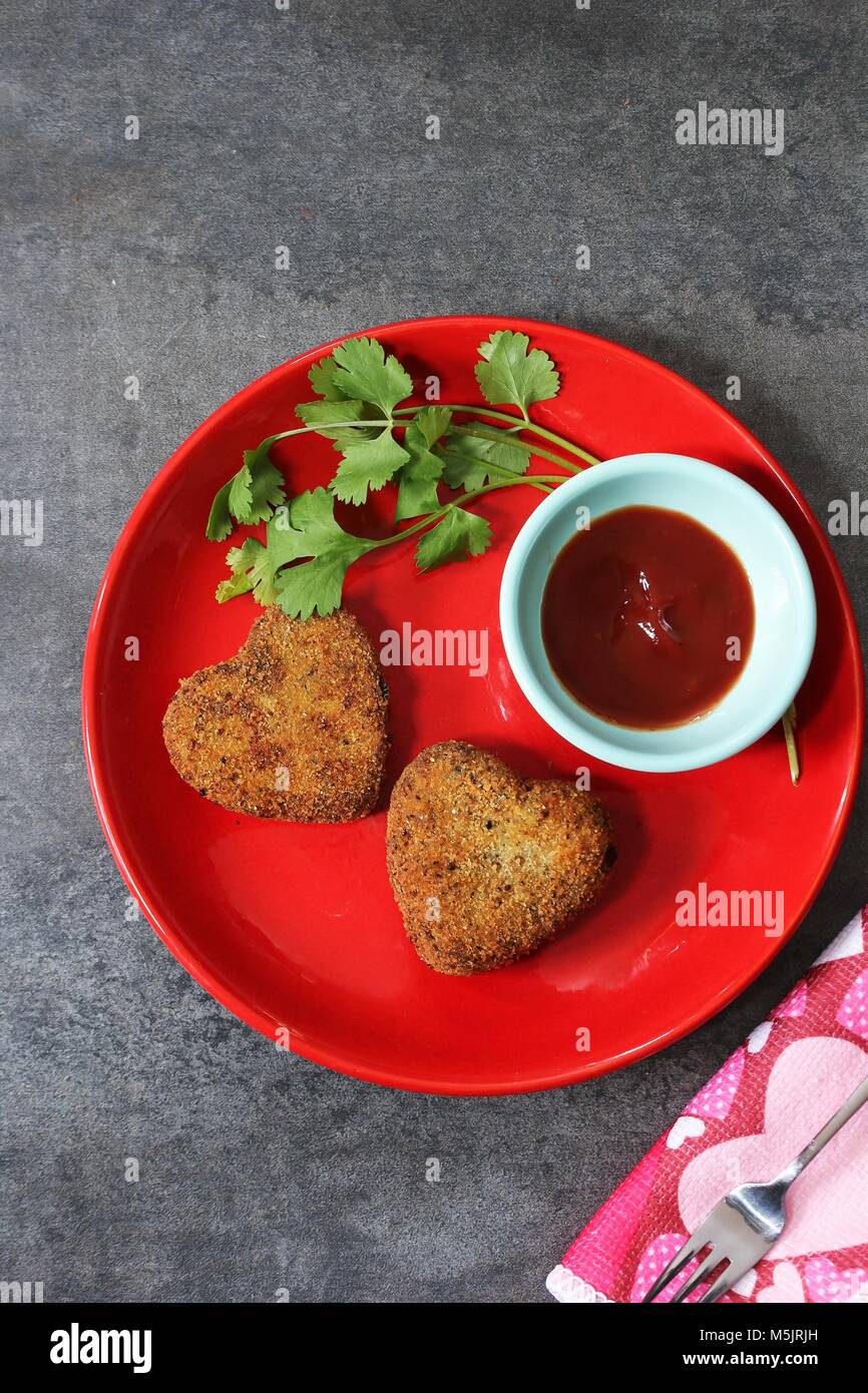 Heart shaped Cutlets in red plate with sauce and cilantro / Valentines ...