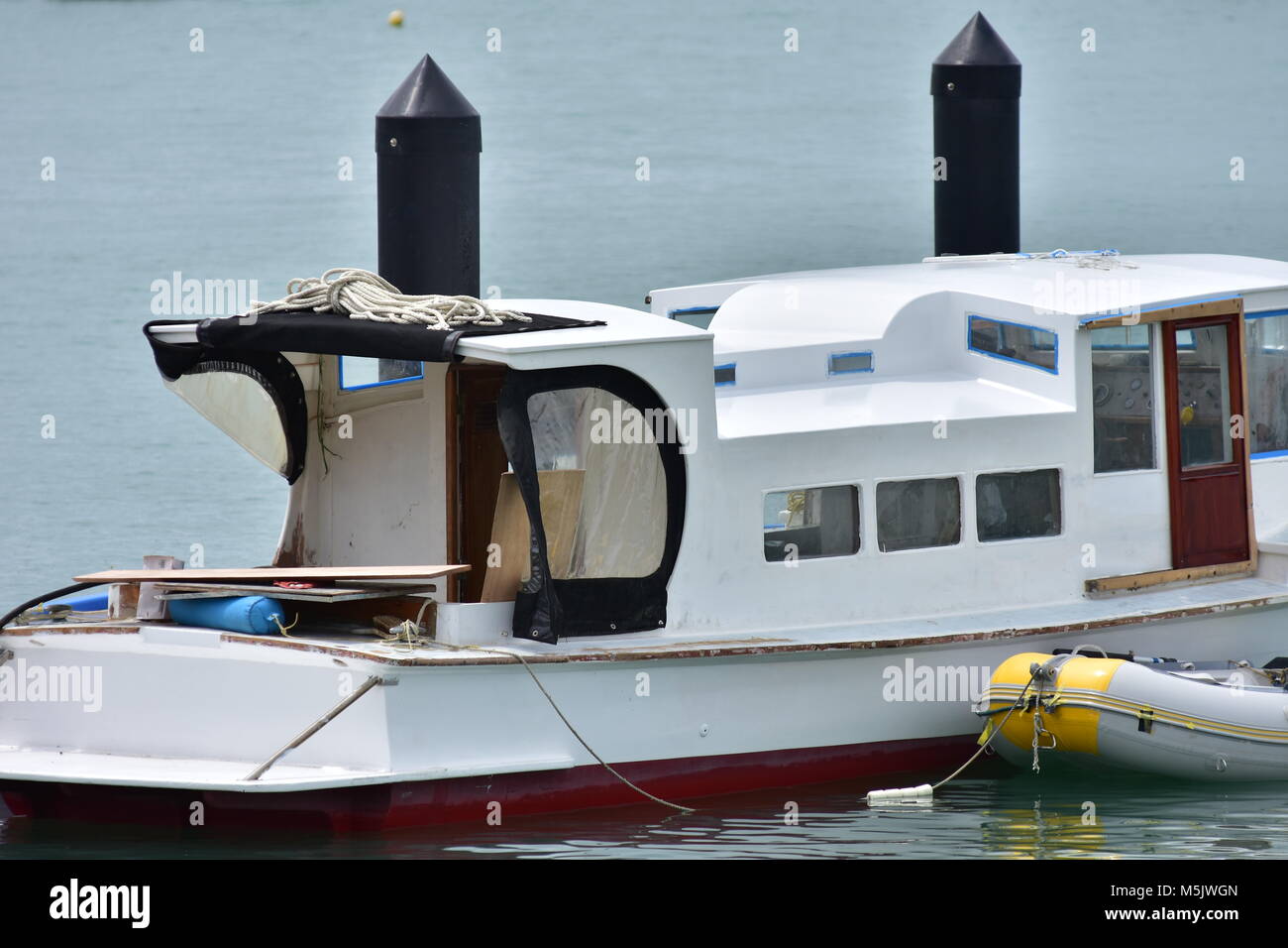 Classic white wooden launch with inflatable dinghy floating pier ...