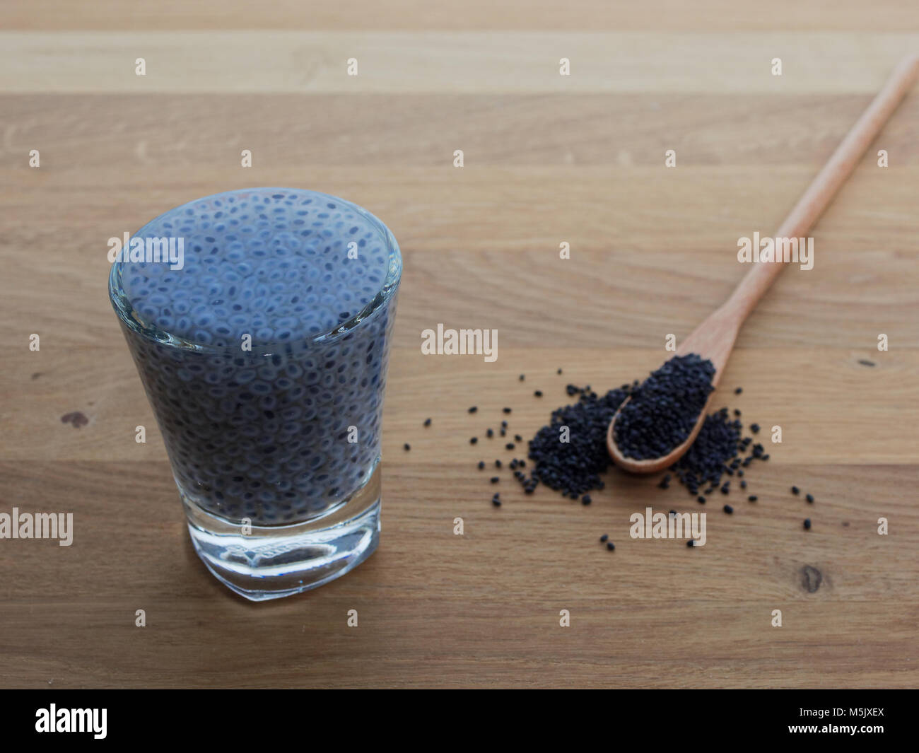 Swelled sweet basil or sabja seeds in shot glass with dried seeds in ...