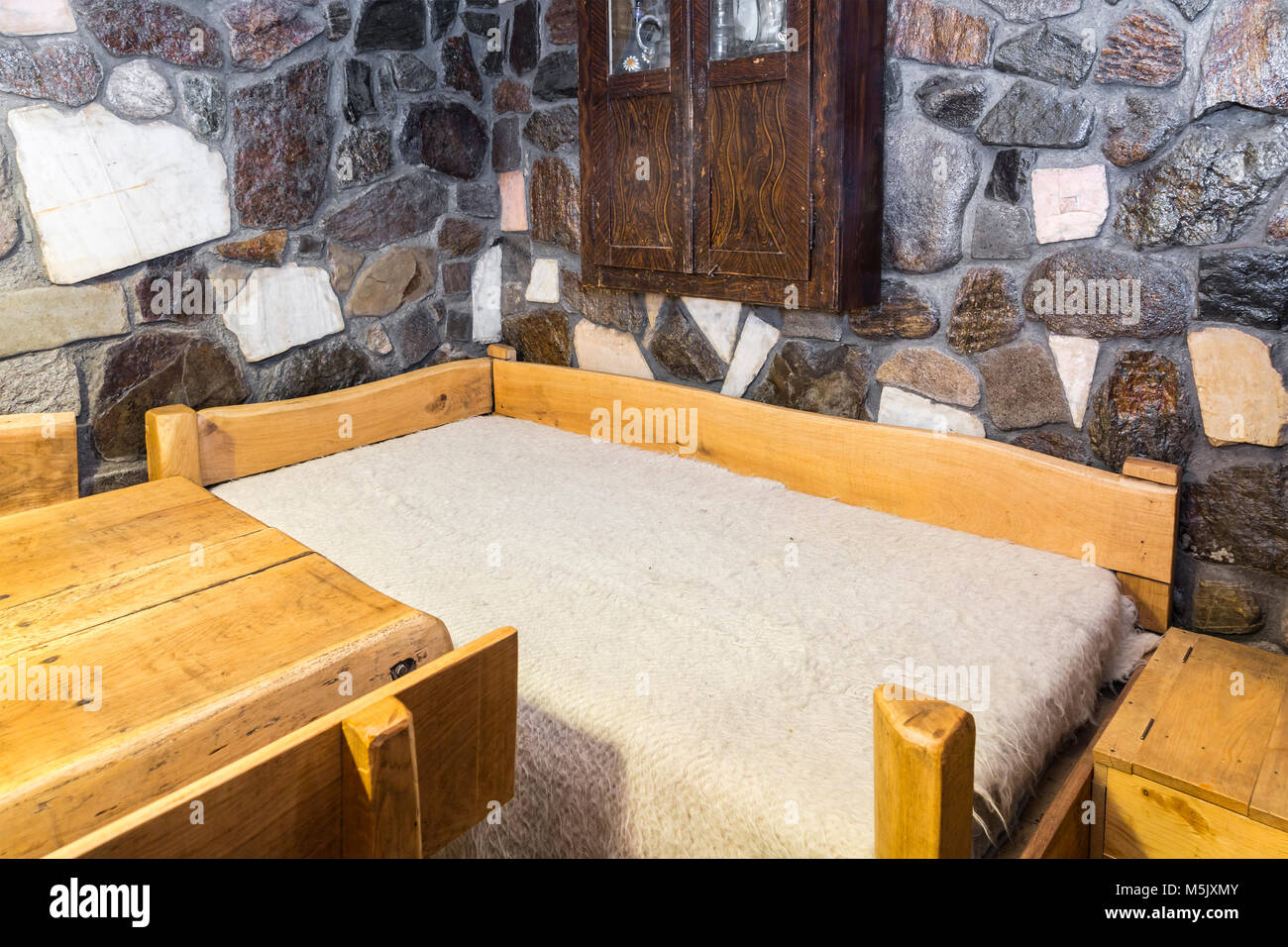 Traditional Romanian wooden bed covered by a whool blanket (cerga) in a ...