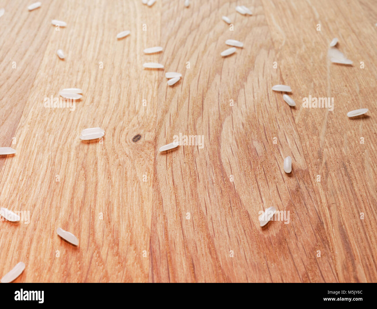 White raw rice spreading over brown wooden background Stock Photo - Alamy