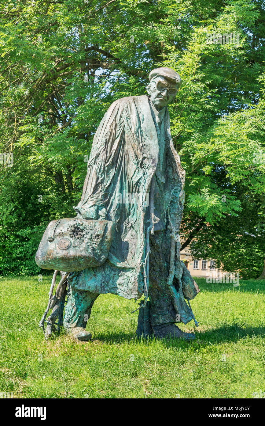 The Bronze Statue Of A Tall Man With A Bag Glasses And Cap Is Located In The Tivoli Park