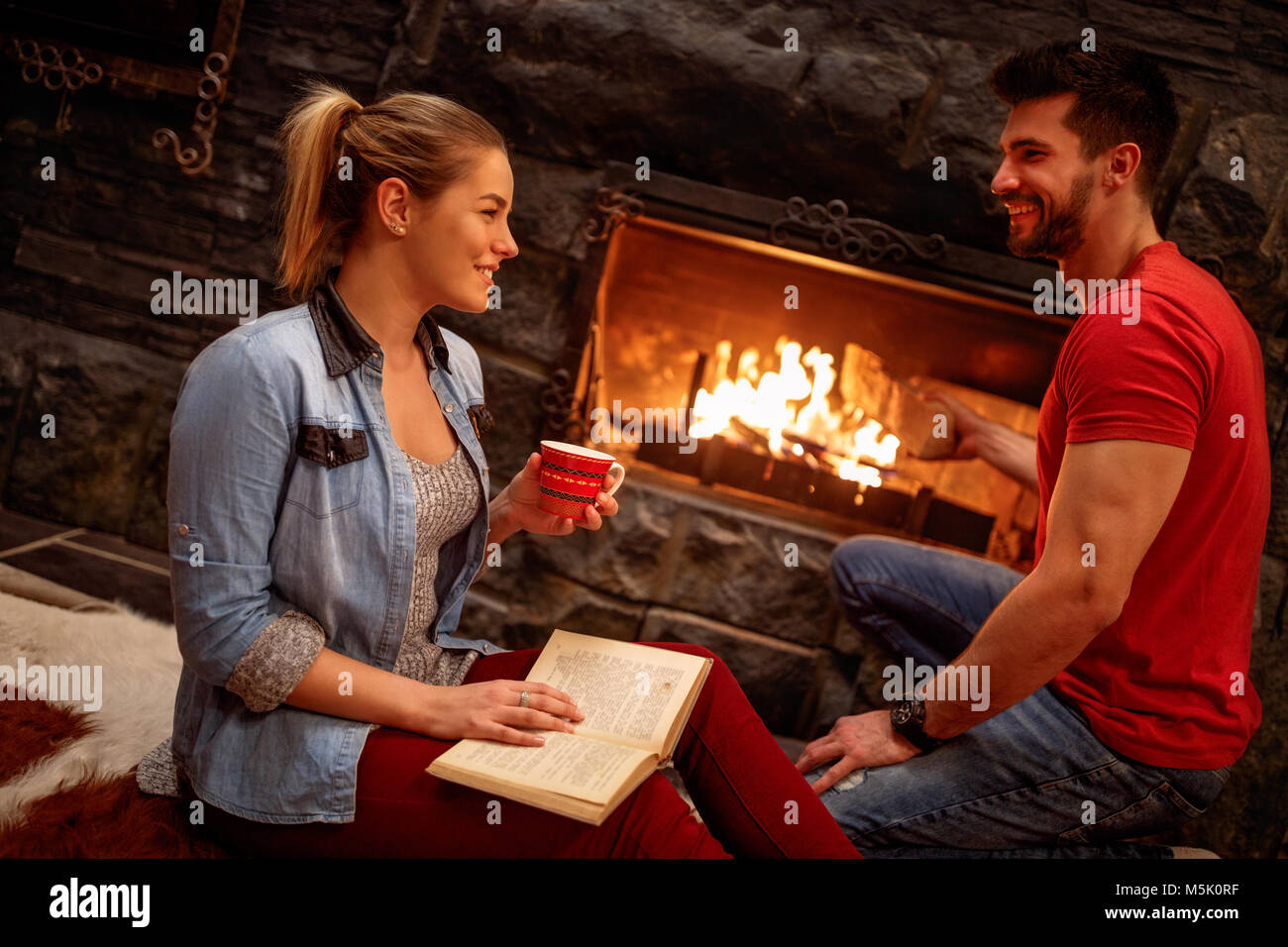 Smiling romantic couple relaxing at home front of fireplace Stock Photo ...