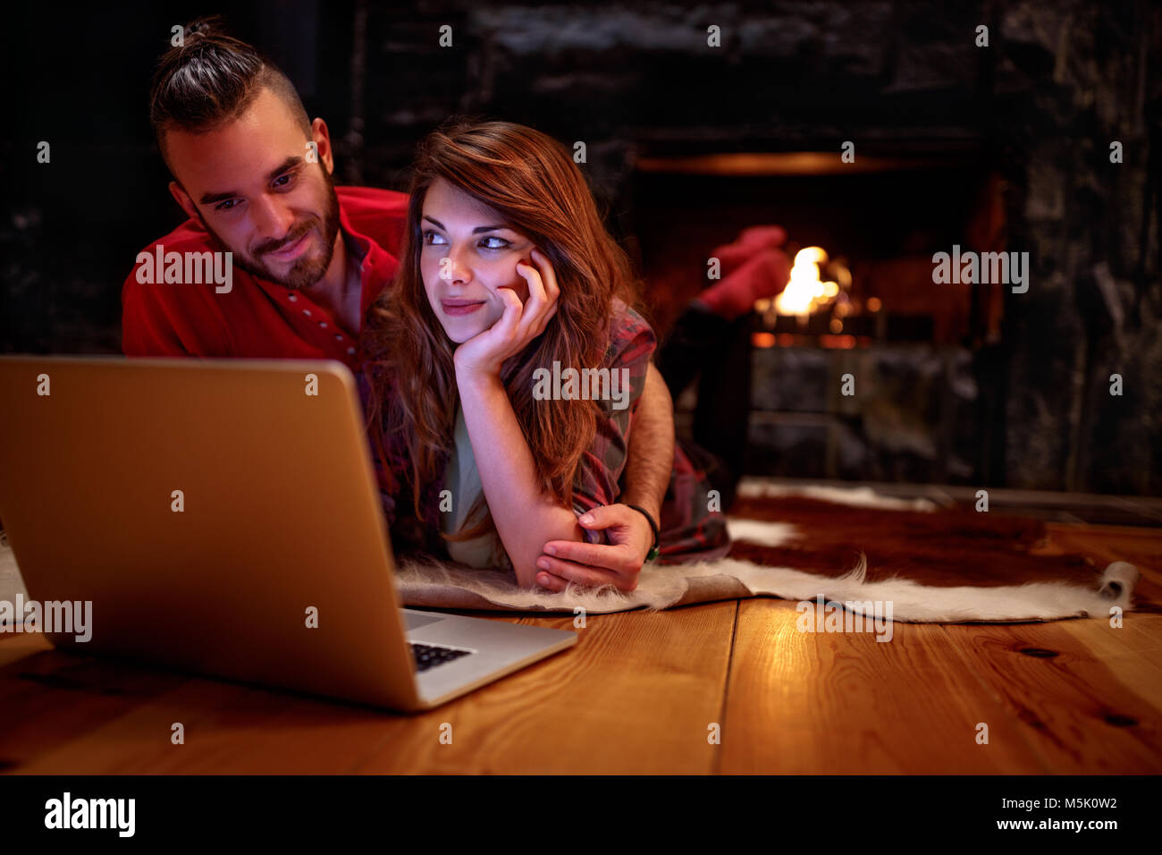 couple laying on floor and using laptop computer at home front of ...