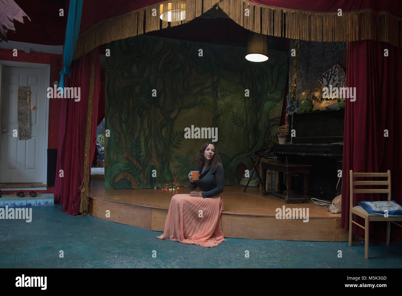 Young female artist sitting on a stage Stock Photo - Alamy