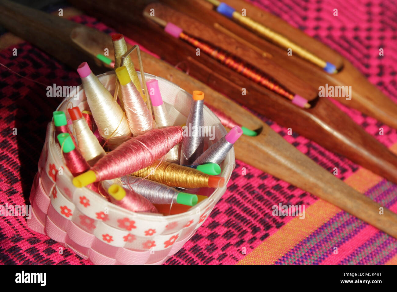 colorful bobbins in basket and wooden bobbin on silk fabric ...