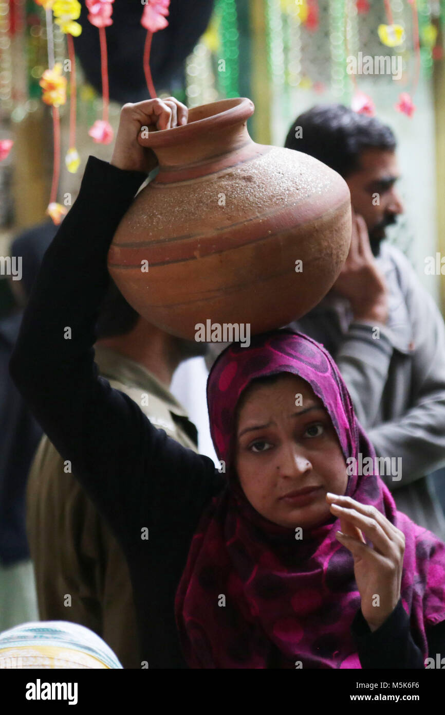 Pakistani women devotees carrying pitchers of rose water for ablution ...