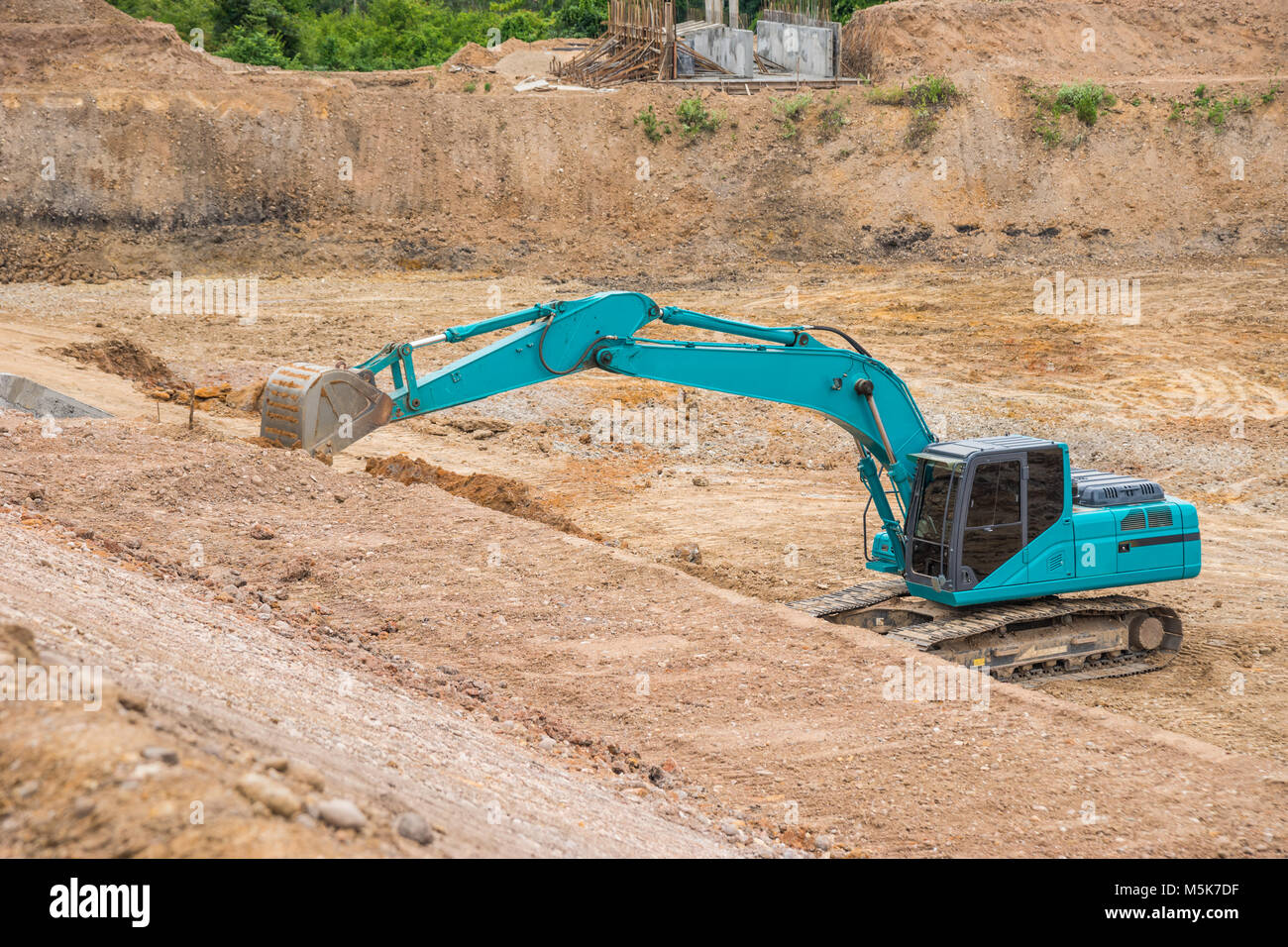 Blue backhoe excavating soil and sand to construct water reservoir ...