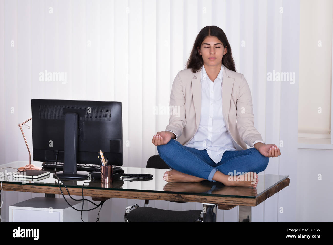 Young Office Female Worker Meditating On Top Of The Desk In Office ...