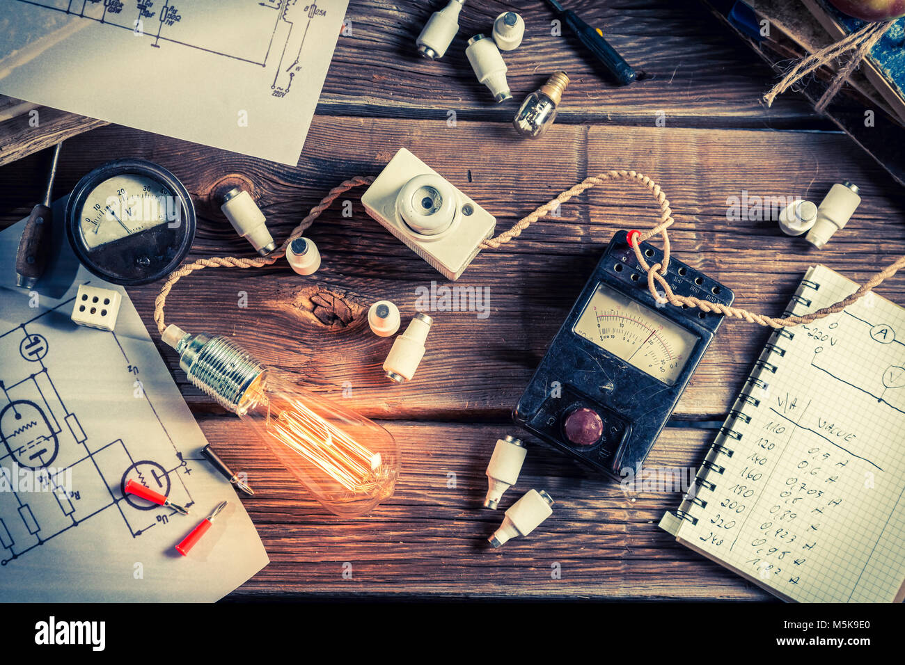 Table with electrical diagrams, a light bulb and books Stock Photo - Alamy