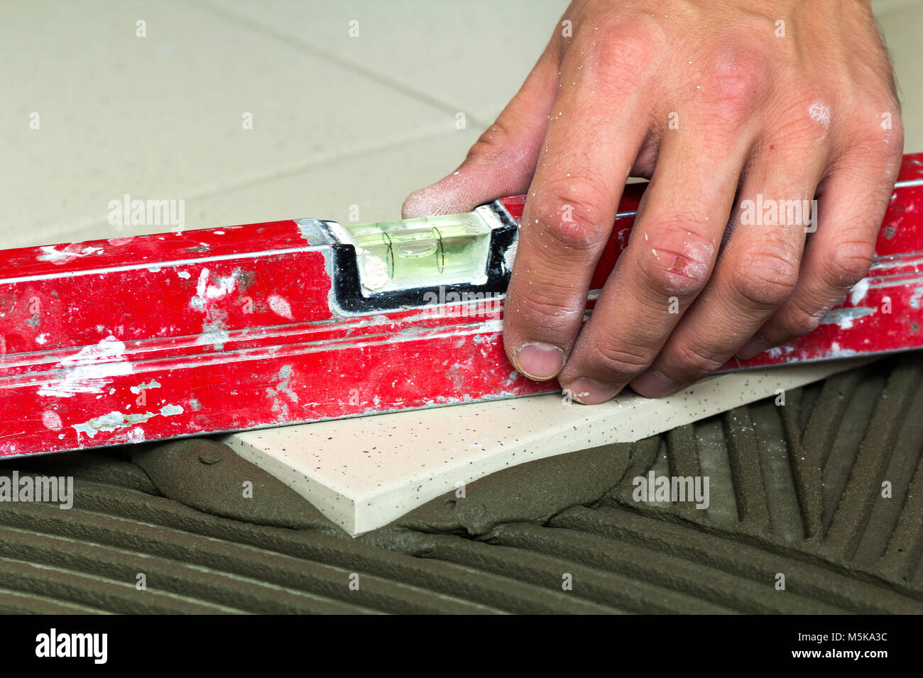 Ceramic tiles and tools for tiler. Worker hand installing floor tiles ...