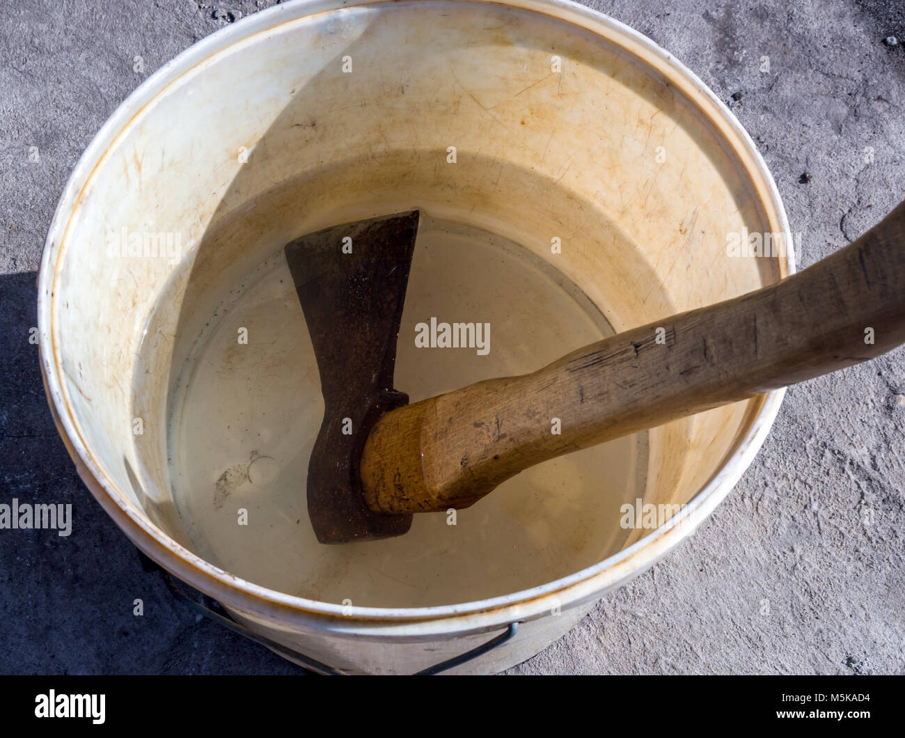 The old ax lies in a bucket of water Stock Photo - Alamy