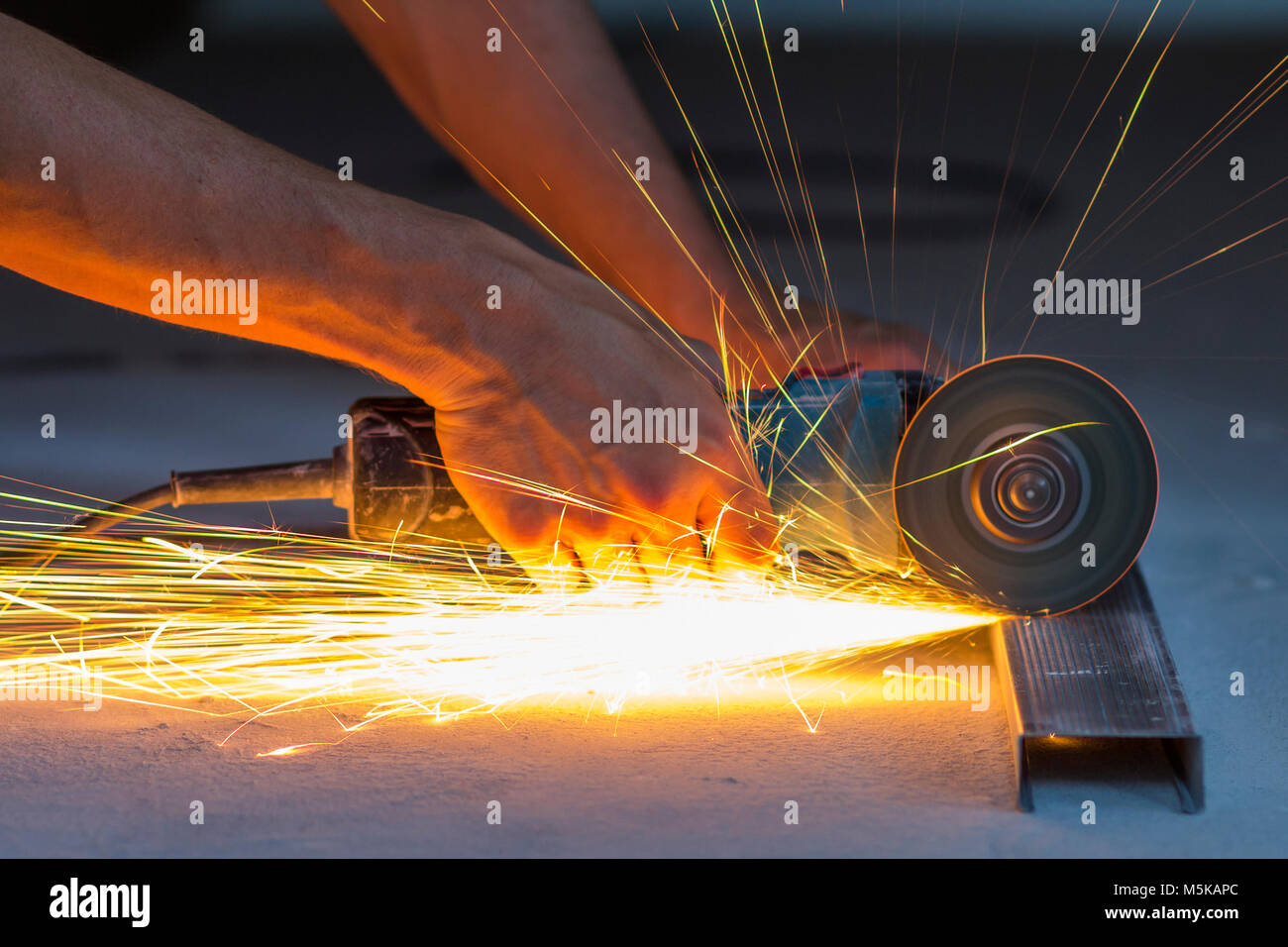 Close-up of worker hands cutting metal with grinder. Sparks while ...