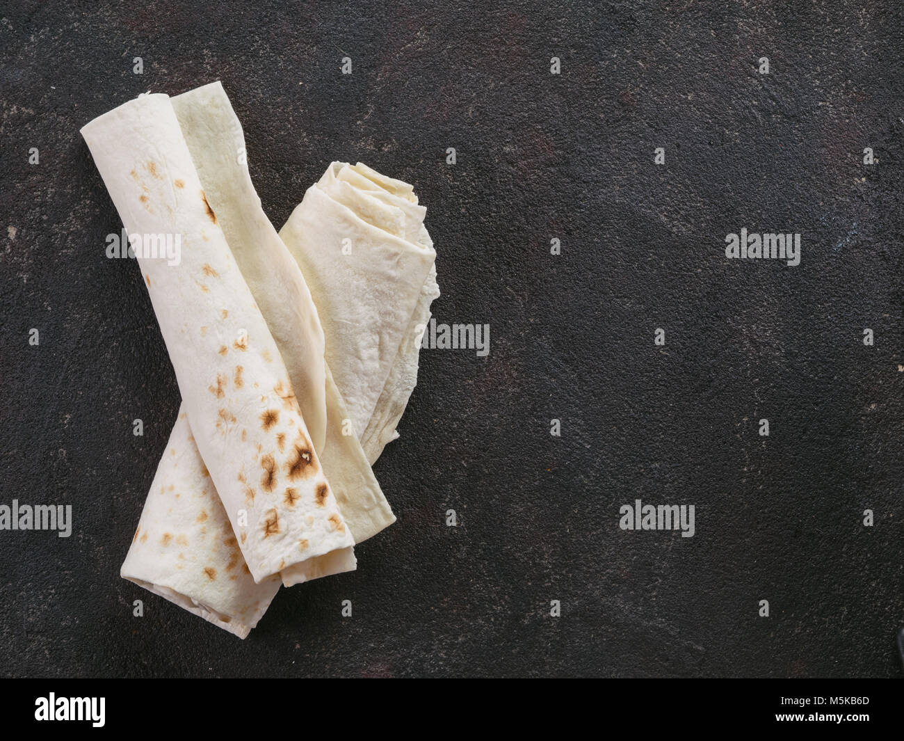 Armenian flat bread lavash. Pita bread on black cement background. Copy ...
