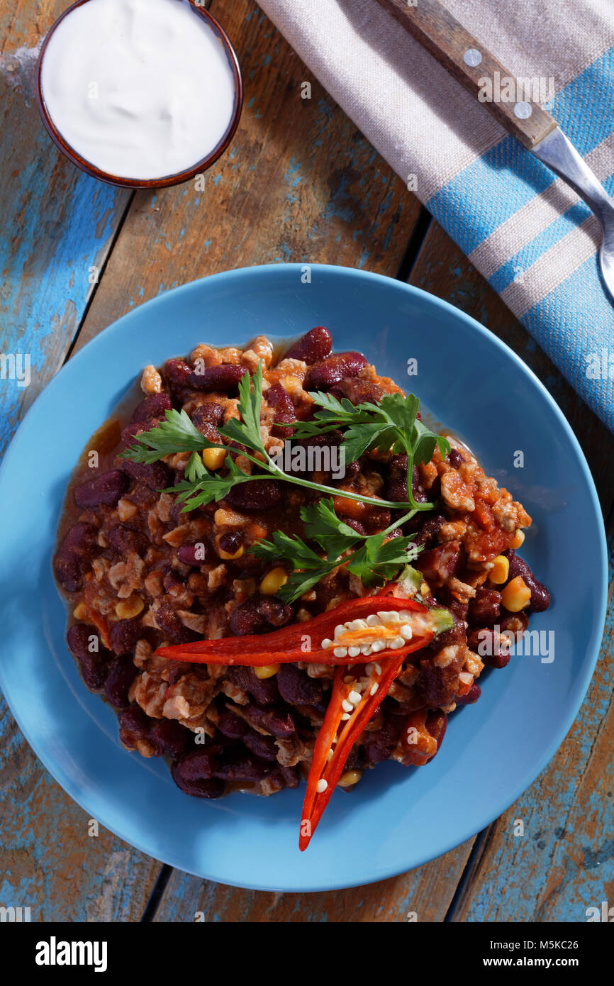 Chili con carne and red chili peppers on a rustic table Stock Photo - Alamy