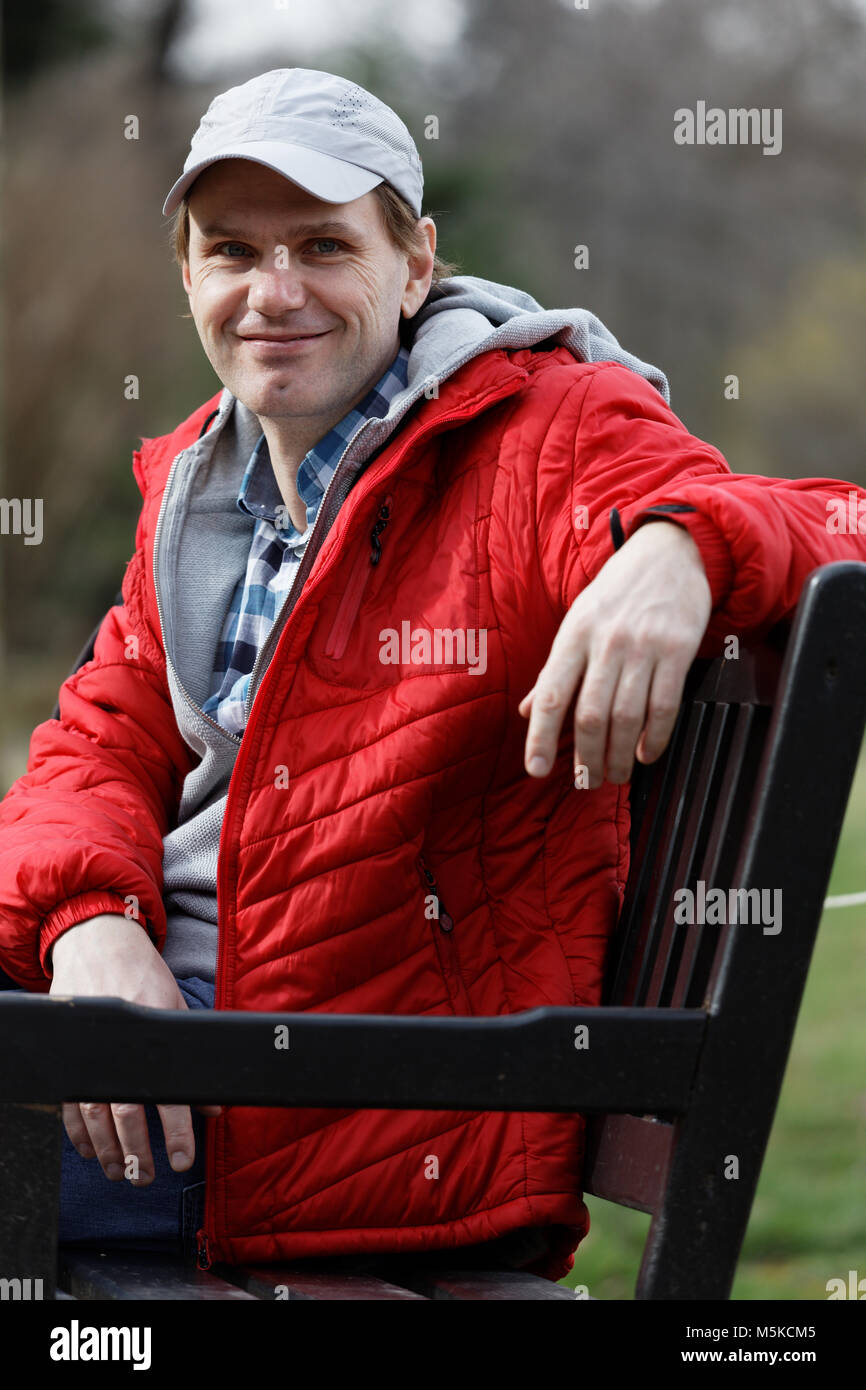 Man sittig on a bench in a park Stock Photo - Alamy