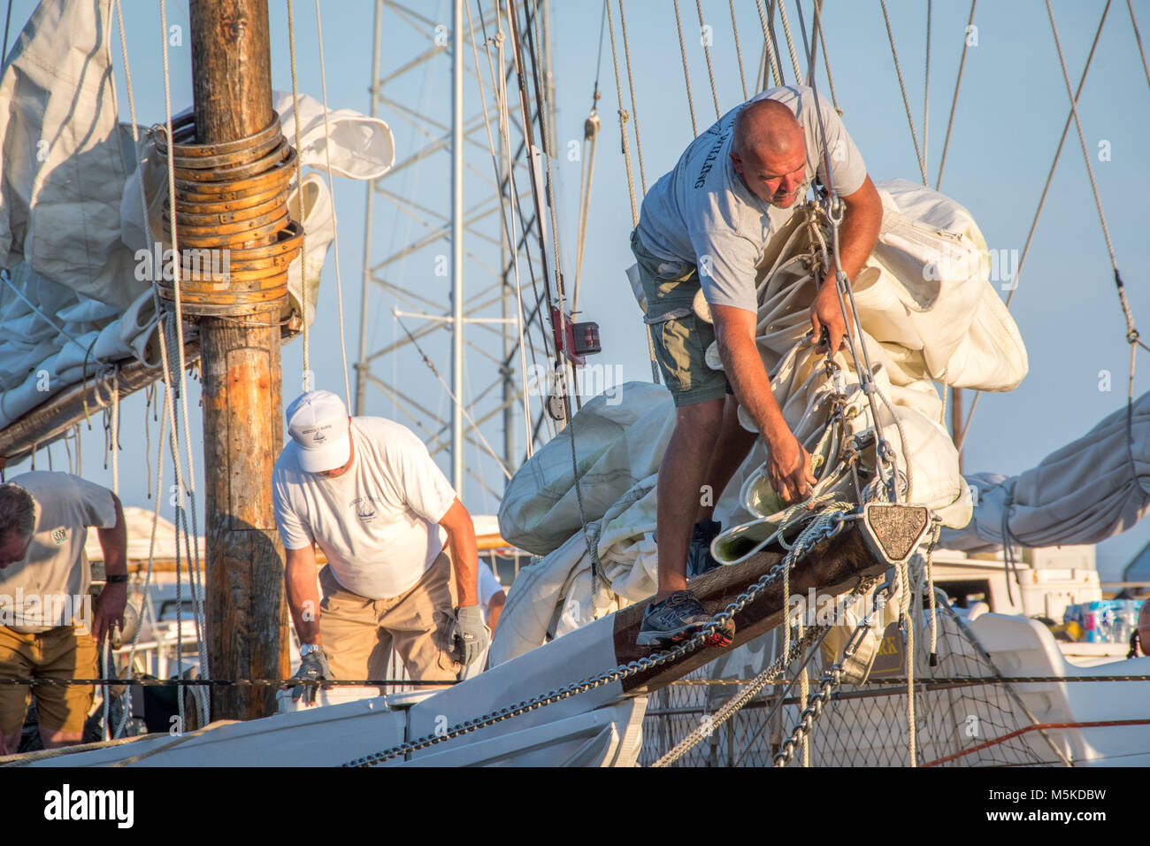 Adult males prepare sails to be hoisted on traditional Skipjack boat ...