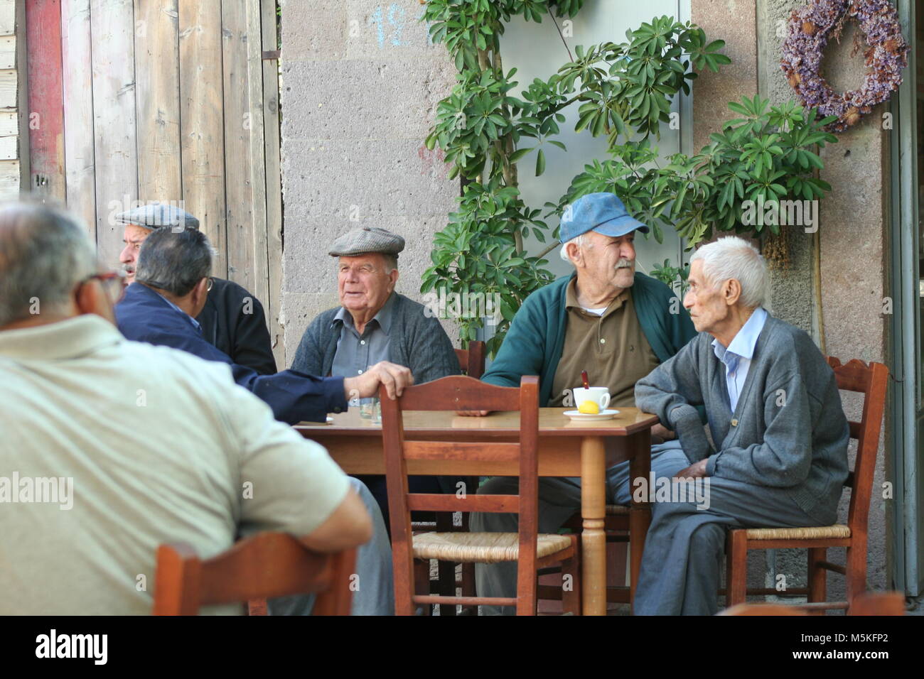 Greek men sitting at a table drinking and chatting Stock Photo - Alamy