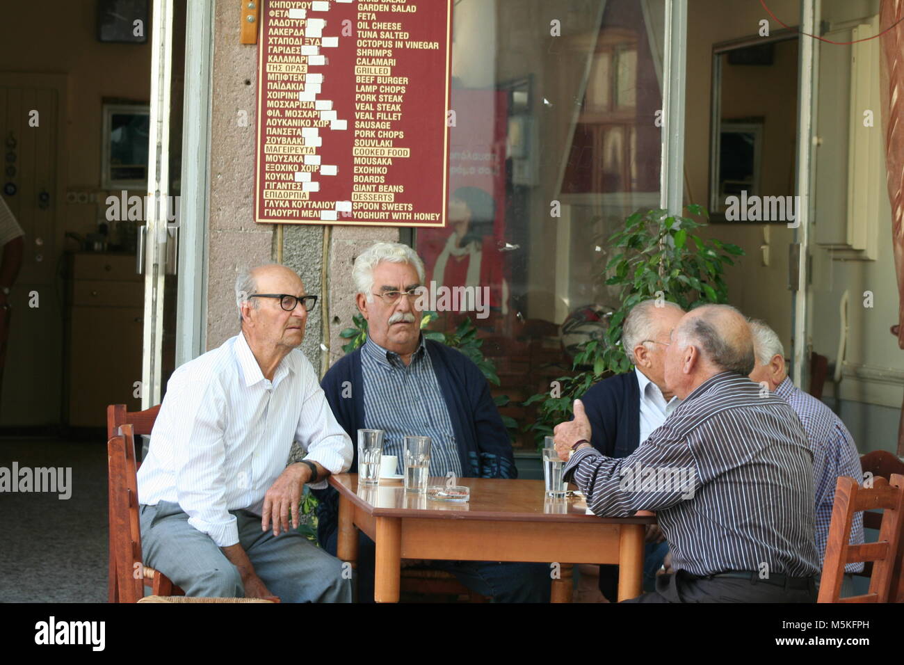 Greek men sitting at a table drinking and chatting Stock Photo - Alamy