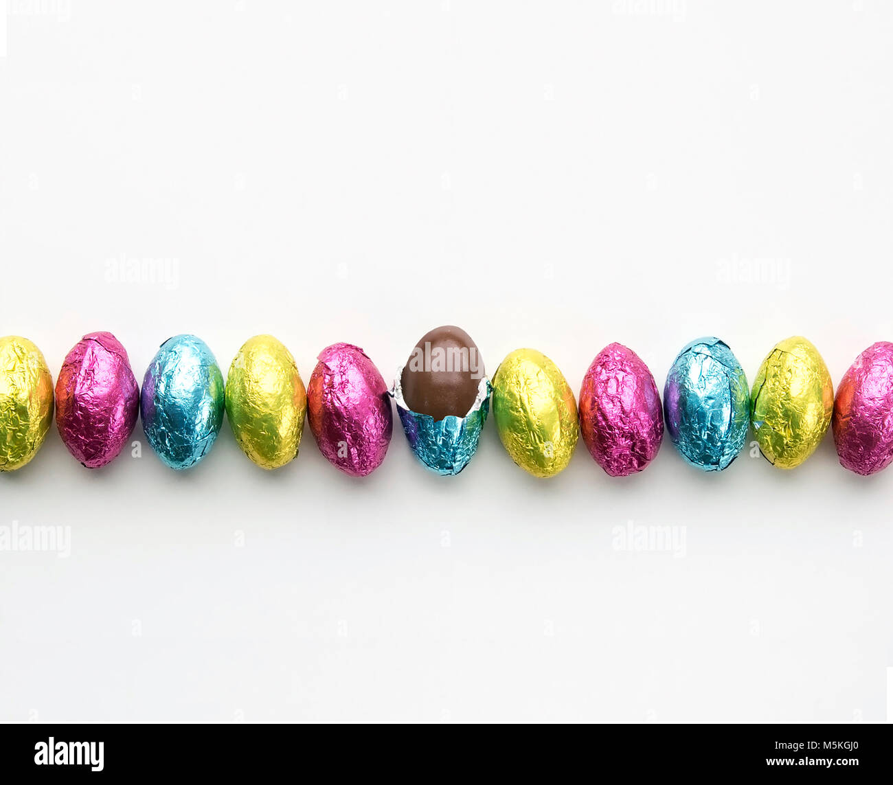 Foil wrapped easter candy in a row one candy unwrapped Stock Photo - Alamy