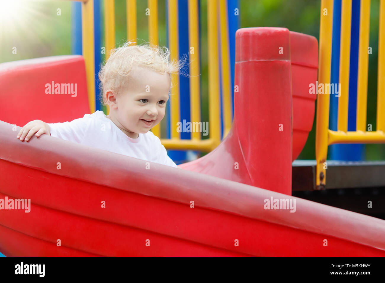 Kids climbing and sliding on outdoor playground. Children play in sunny ...