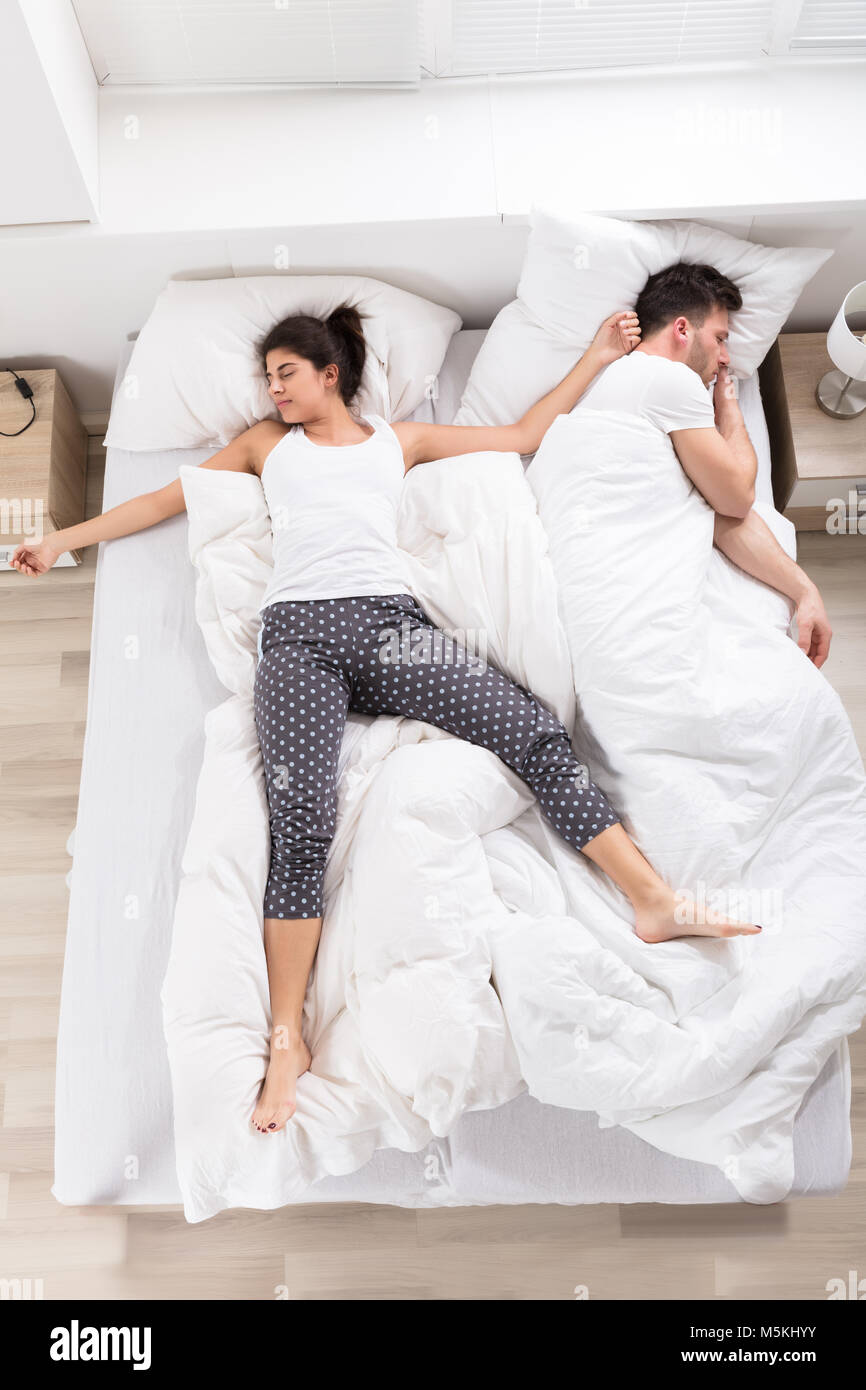 Overhead View Of Young Woman Sleeping Beside Her Husband On Bed Stock ...