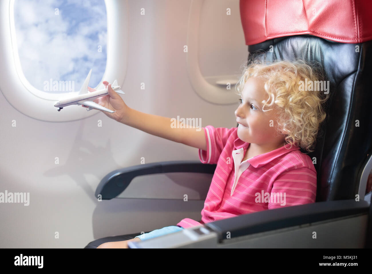 Child in airplane. Kid in air plane sitting in window seat. Flight ...