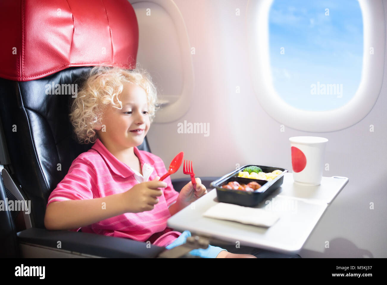 Child in airplane window seat. Kids flight meal. Children fly. Special ...