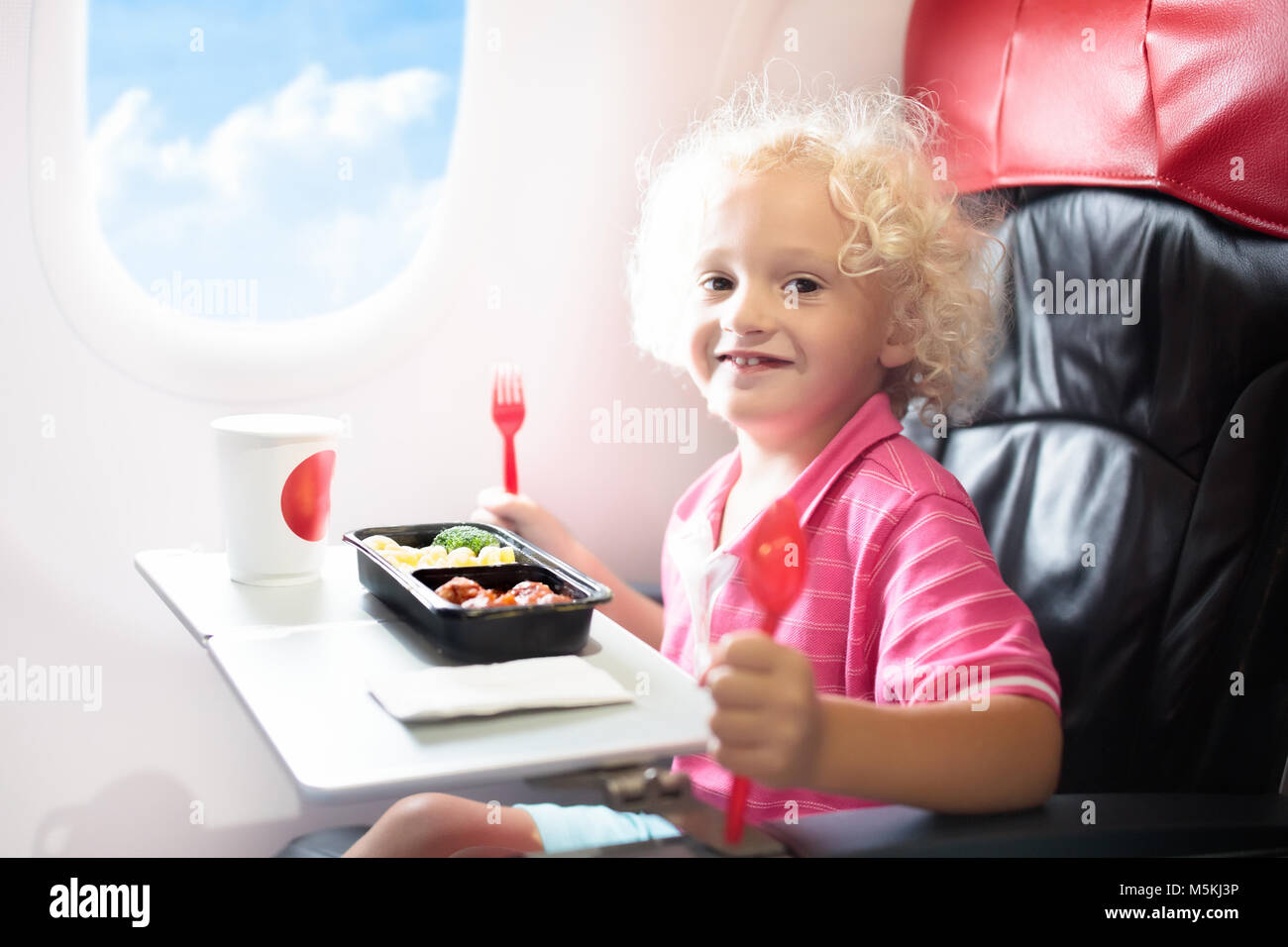 Child in airplane window seat. Kids flight meal. Children fly. Special ...