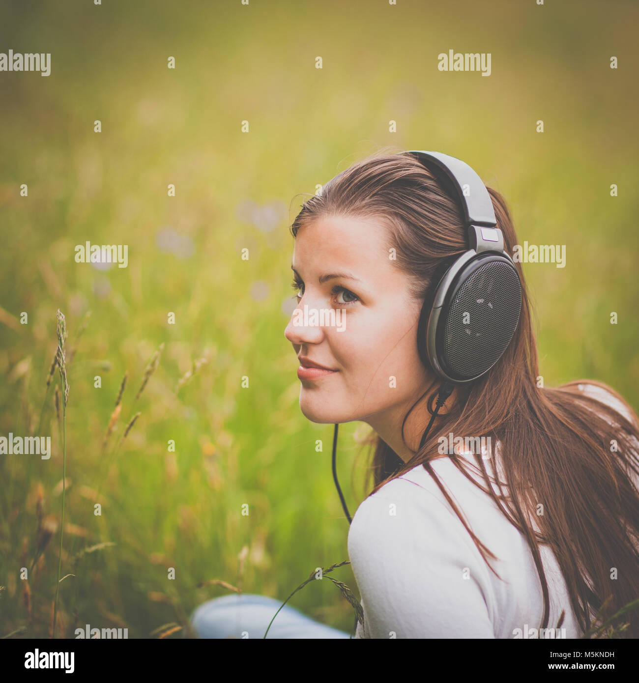 portrait of a pretty young woman listening to music on her mp3 player ...