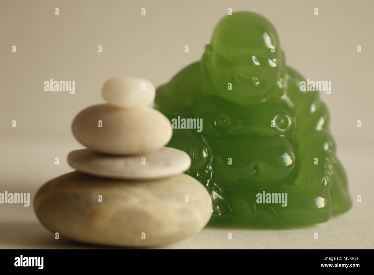 White pebble stones and a green Buddha Stock Photo - Alamy