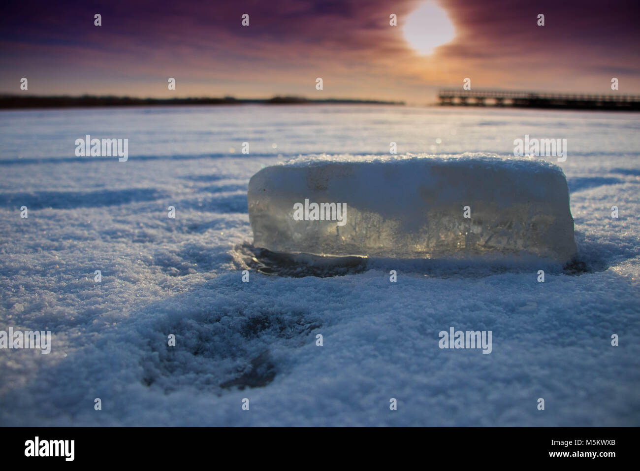 ice brick laying on the frozen ake, shining at morning sun rays at ...