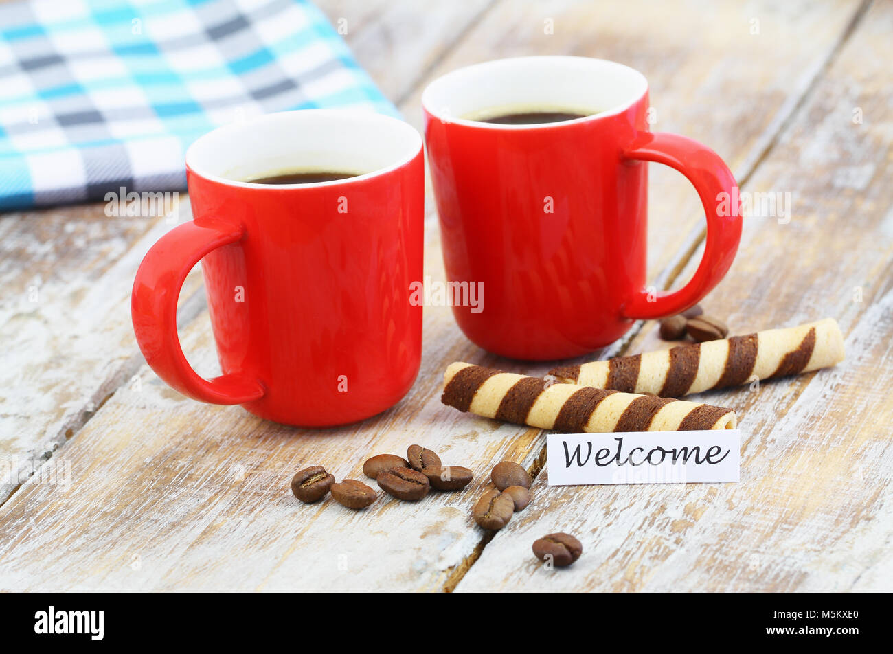 Welcome card with two red mugs with coffee and coffee beans on rustic ...
