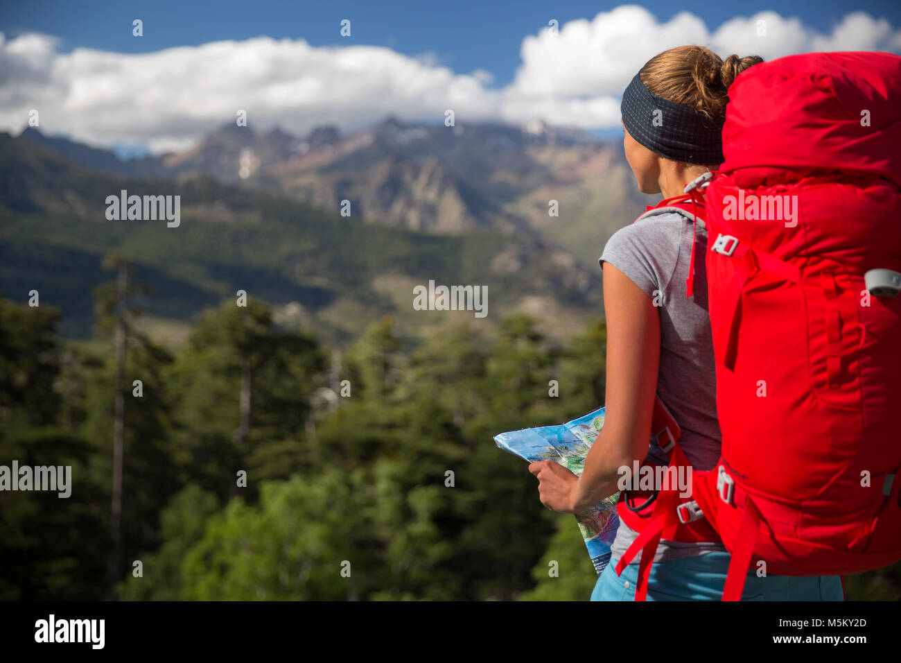 Pretty, female hiker in high mountains packing her backpack Stock Photo ...