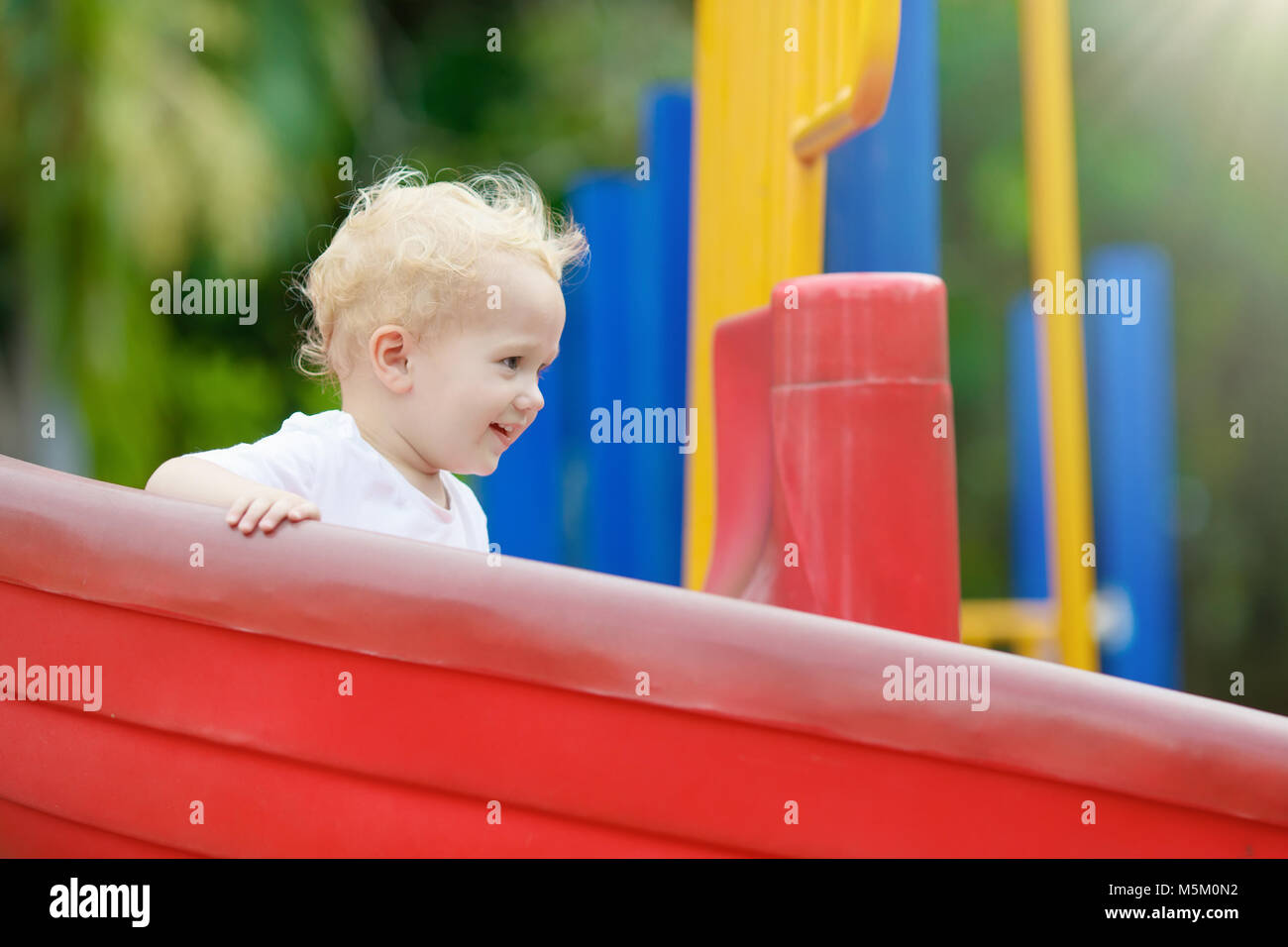 Kids climbing and sliding on outdoor playground. Children play in sunny ...