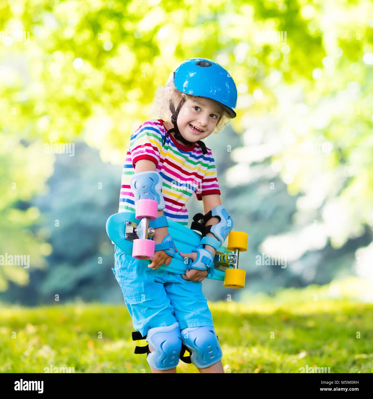 Child riding skateboard in summer park. Little boy learning to ride ...