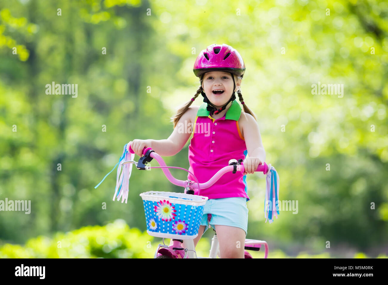 Child riding bike. Kid on bicycle in sunny park. Little girl enjoying ...