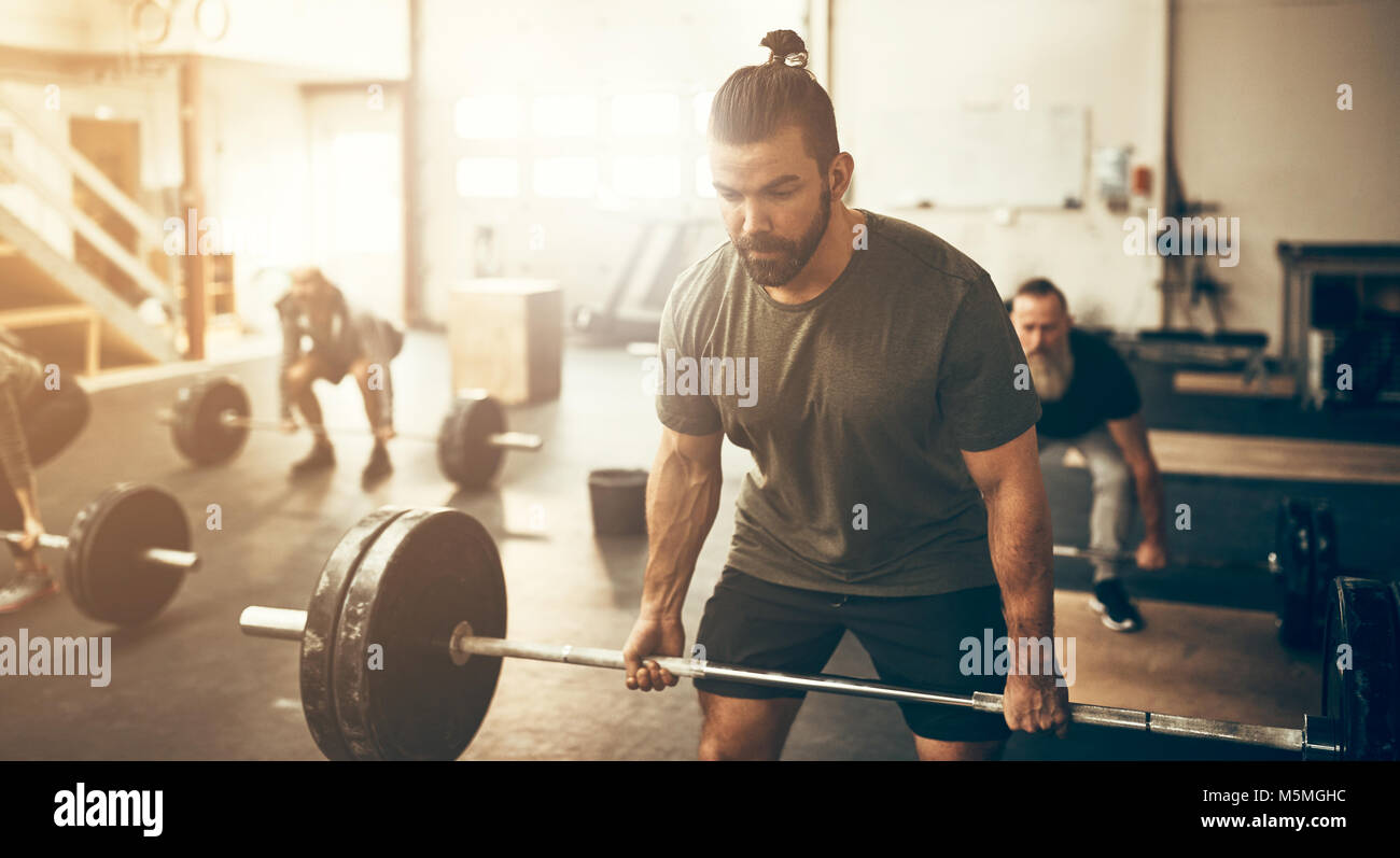 Fit young man in sportswear straining while lifting heavy weights ...
