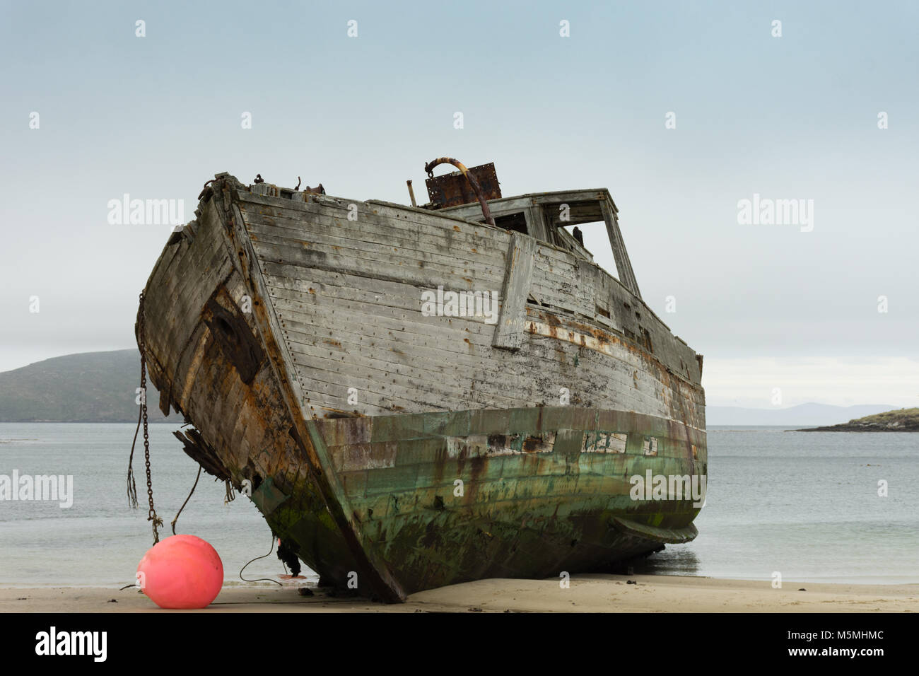 Close up of an old wooden shipwrecked boat run aground on a tan sandy ...