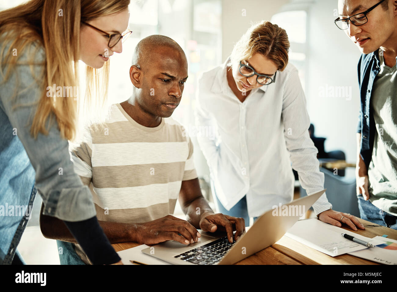 Diverse group of focused young work colleagues standing together at an ...