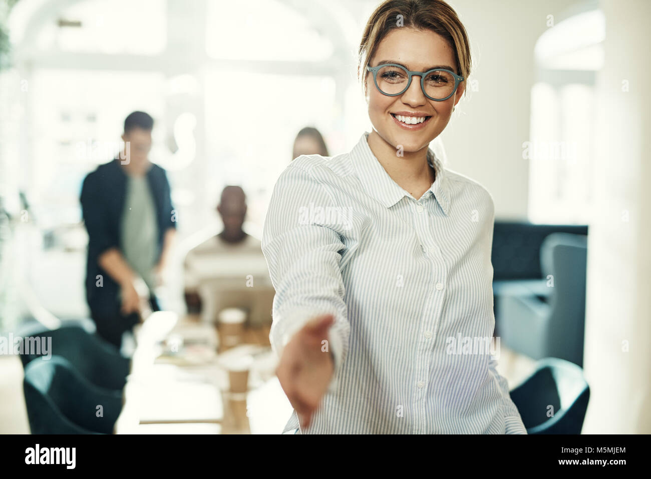Smiling young businesswoman extending a handshake while standing in an ...