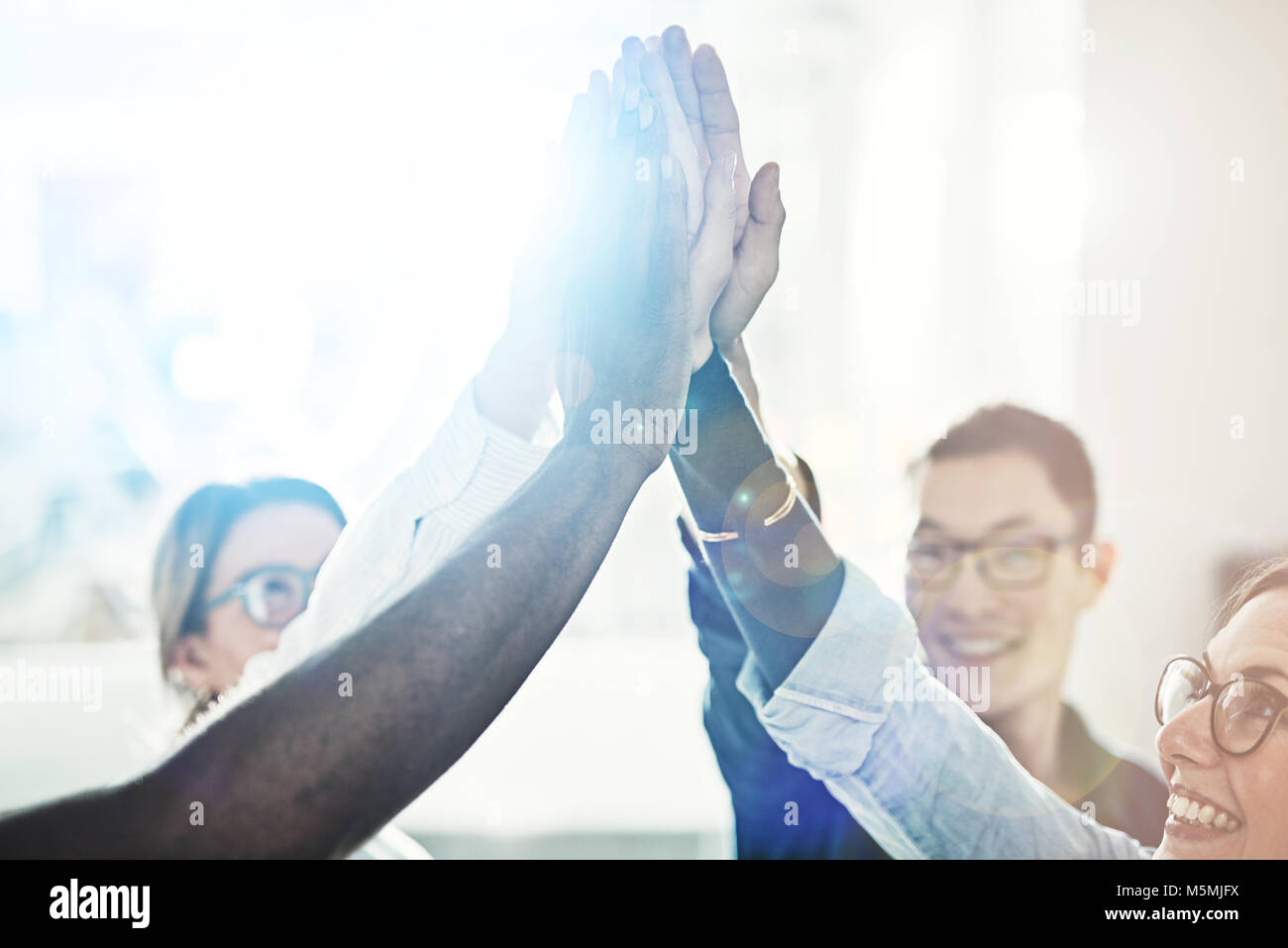 Smiling group of diverse businesspeople high fiving each other while ...