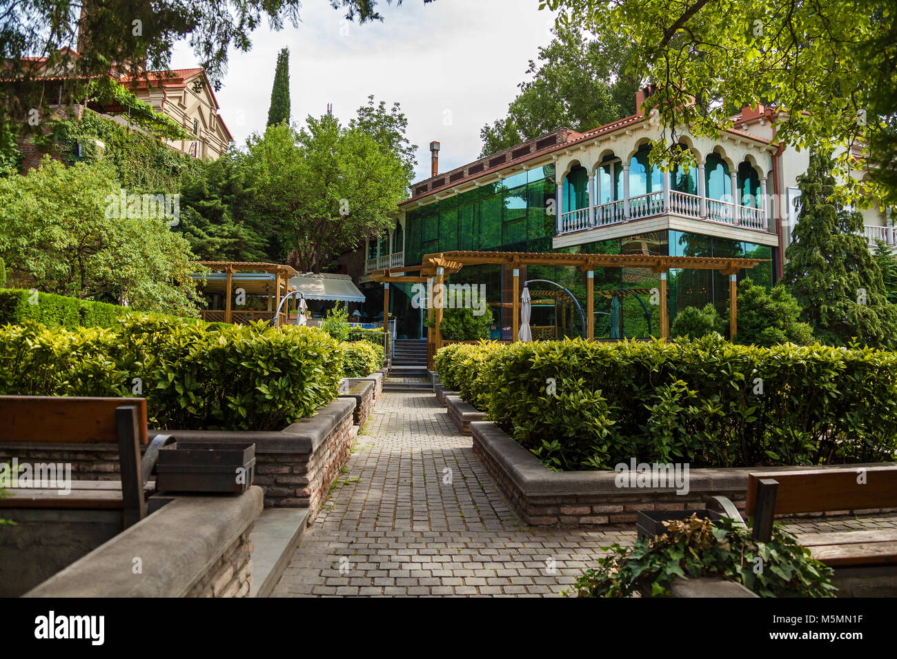 The benches, bushes, trees on the background of the hotel. Alley ...