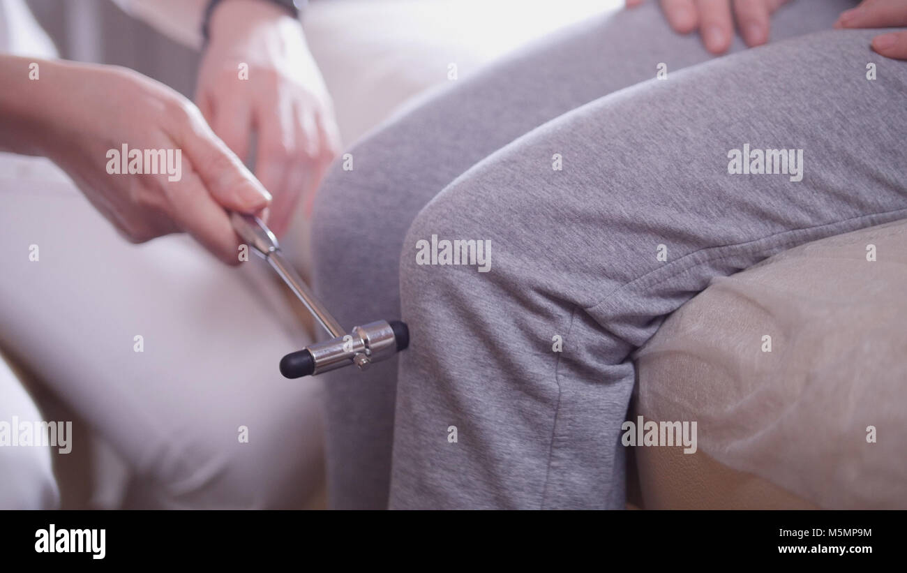 Doctor the neurologist examines the patient taps with a hammer on the ...