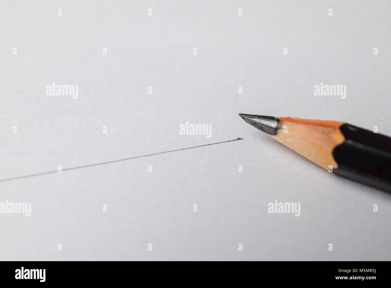 Drawing a line on white paper with a pencil - close-up Stock Photo - Alamy