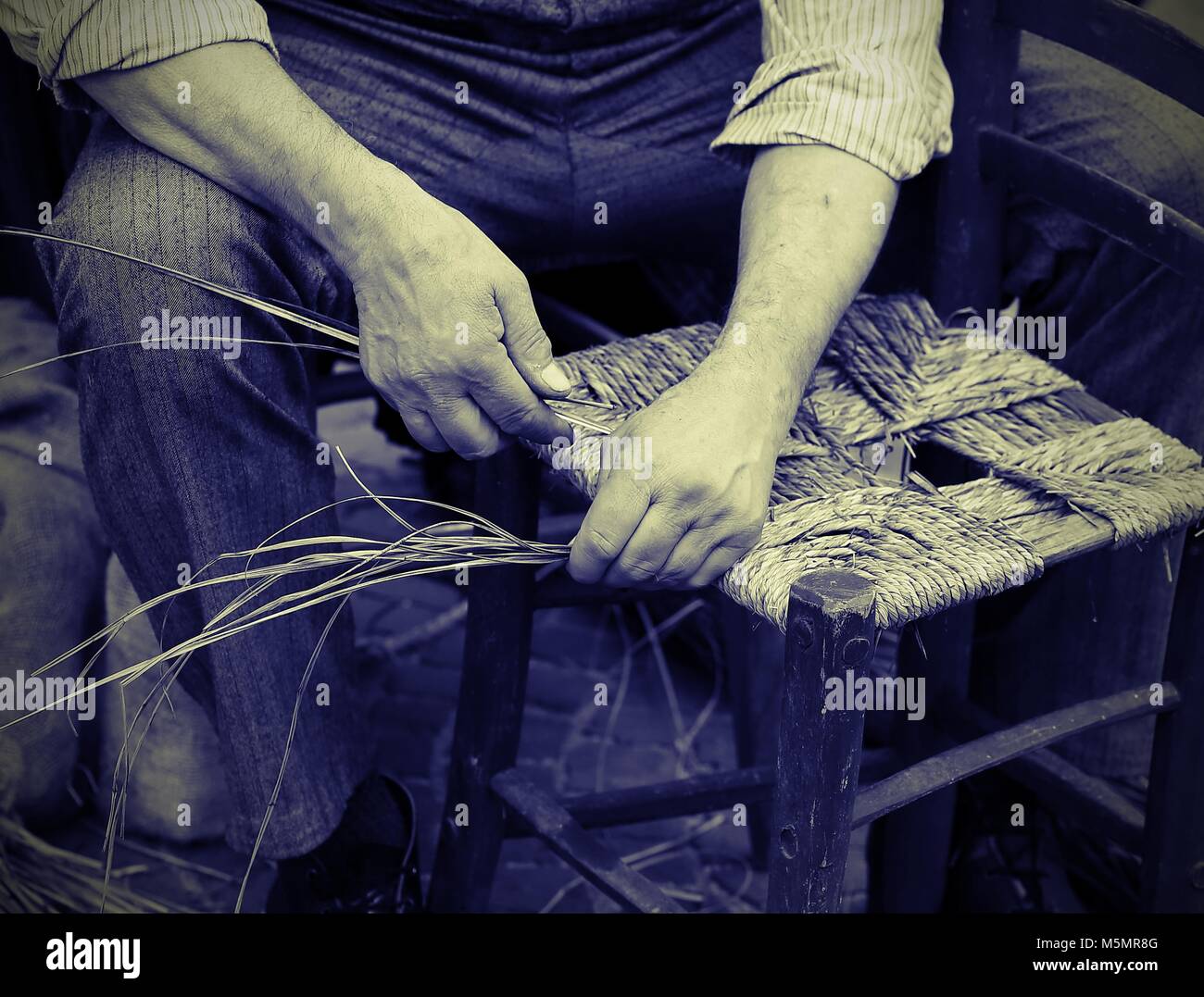 man mender of chairs while repairing old chair with vintage effect ...