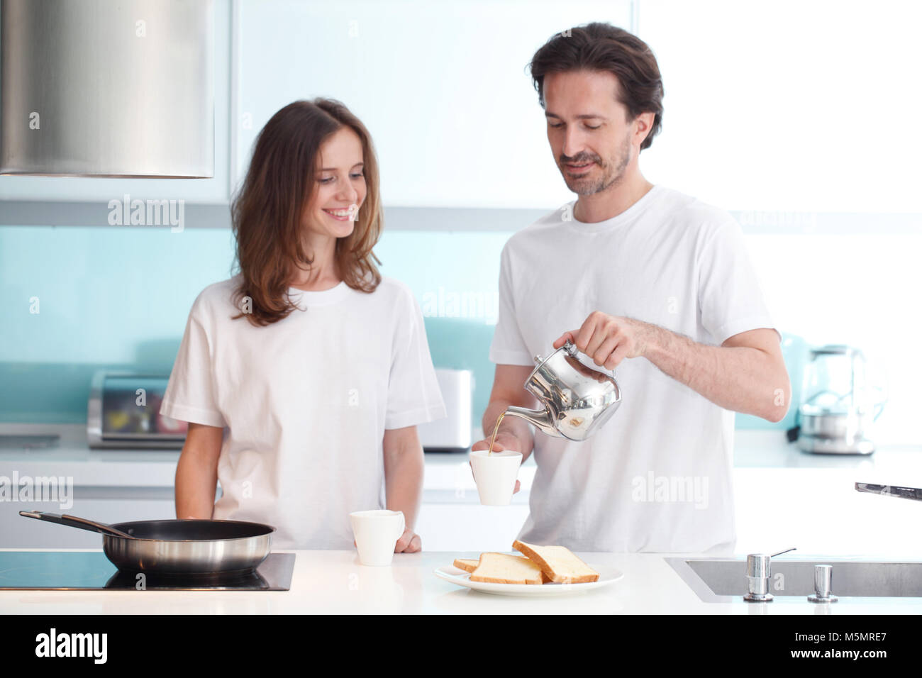 Happy couple cooking breakfast together in the kitchen Stock Photo - Alamy