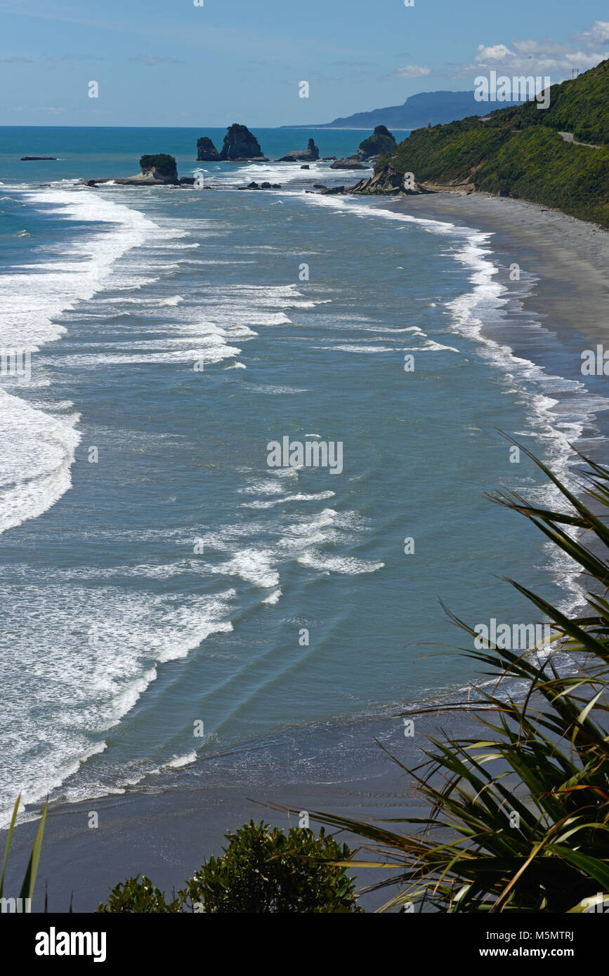 native bush frames a beach at low tide on a West Coast beach, South ...